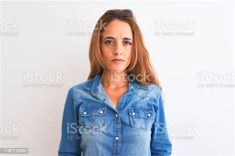 젊은 빨간 머리 여자 데님 재킷을 입고 얼굴에 심각한 표정으로 고립 된 배경 위에 서 카메라를 보는 간단하고 자연스러운 결심에 대한 스톡 사진 및 기타 이미지 Istock