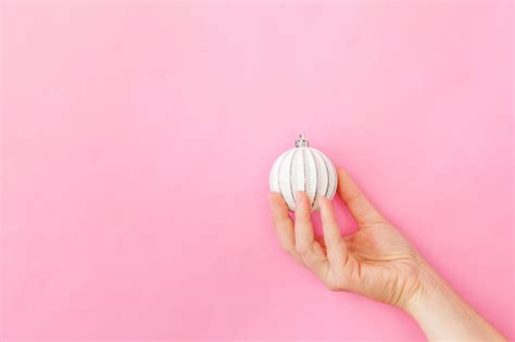 분홍색 파스텔 컬러의 트렌디 한 배경에 고립 된 크리스마스 장식 공을 들고 있는 최소한의 디자인 여성 12월에 대한 스톡 사진 및 기타 이미지 Istock