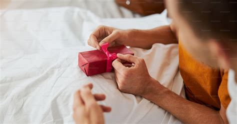 아름 다운 빨간 패키지에 포장 된 선물 상자에 리본을 푸는 남성 손의 클로즈업 사진 Unsplash의 게이 커플 이미지