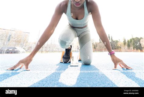 Black Woman On Starting Blocks In Crouch Position Getting Ready For Sprint At Stadium Stock