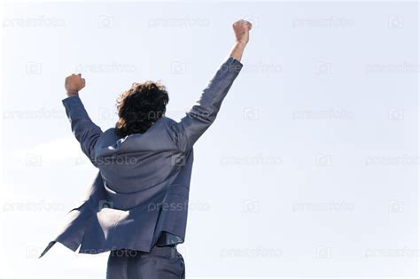 Фотография на тему Мужчина в костюме стоит спиной к камере подняв руки вверх Pressfoto