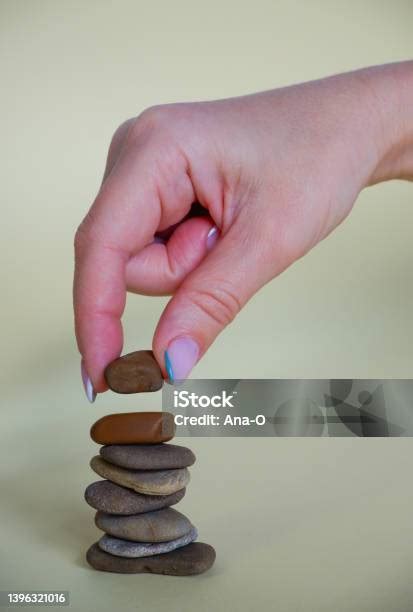 바위 균형 노란색 배경에있는 여성의 손이 서로 위에 작은 바다 돌을 놓습니다 밸런스드 스톤 또는 밸런싱 록 선 개념 명상 돌 바위에 대한 스톡 사진 및 기타 이미지 Istock