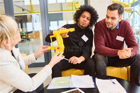 Engineers Discussing Robot Gripper In A Robotics Workshop Focusing On
