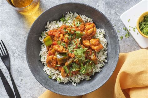 A Bowl Filled With Rice Meat And Vegetables Next To A Glass Of Beer On A Table
