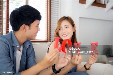 아름 다운 초상화 젊은 아시아 몇 남자를 들고 단어 사랑 함께 거실 가족 남편과 아내와 함께 웃 고 행복 소파에 앉아 고 긴장 라이프 스타일 개념으로 캐주얼 입고 여자 애