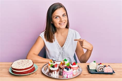 젊은 백인 여자 먹는 패스트리 가리키는 손가락 에 한 자기 미소 행복 하 고 자랑 케이크에 대한 스톡 사진 및 기타 이미지 케이크 가리키기 보여주기 Istock