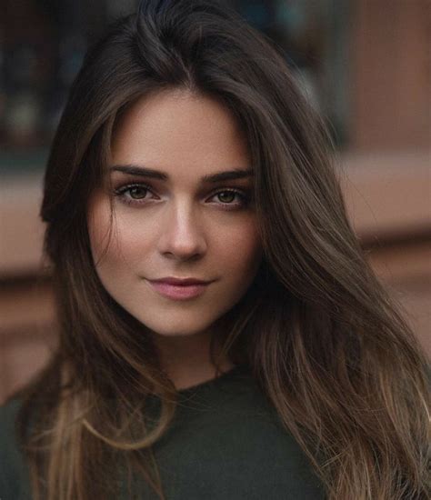 A Close Up Of A Person With Long Hair Wearing A Green Shirt And Looking