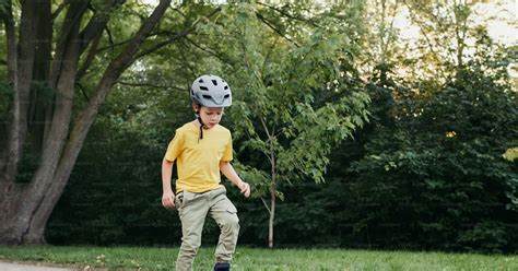 여름날 공원의 도로에서 스케이트보드를 타는 회색 헬멧을 쓴 행복한 백인 소년 계절에 따라 야외 어린이 활동 스포츠 건강한 어린 시절의 생활 방식 스케이트 보드를 타는