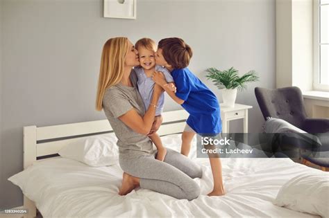 어머니와 아이들은 방에 침대에서 껴안고 키스합니다 어머니의 날 엄마와 아들들은 껴안습니다 18 23 개월에 대한 스톡 사진 및 기타 이미지 Istock
