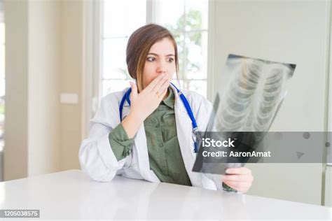 실수 공포의 표정 침묵 비밀 개념에 의해 수치심으로 충격을 받은 손으로 가슴 방사선 표지 입을 바라보는 아름다운 젊은 의사 여성 X 레이에 대한 스톡 사진 및 기타 이미지