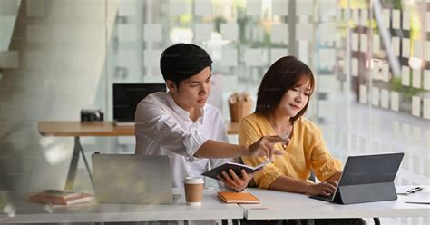 컴퓨터 태블릿으로 작업하고 현대적인 사무실 위의 긴 흰색 작업 책상에 함께 앉아 있는 웹사이트 관리자고객 지원 팀의 사진 사진 Unsplash의 유지 이미지