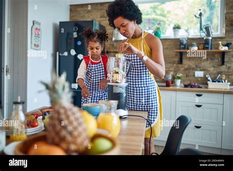 Mother And Her Young Daughter Coming Together To Prepare A Healthy Meal Immersed In The Process