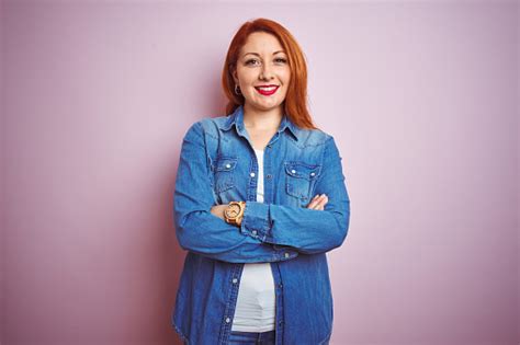 Youg 아름다운 빨간 머리 여자 데님 셔츠 위에 서 고립 된 분홍색 배경 행복 한 얼굴 카메라를 보고 교차 팔 미소 긍정적 인 사람 T 셔츠에 대한 스톡 사진 및 기타