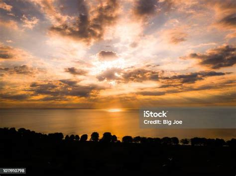 화려한 주황색과 파란 흐린 하늘 아래 물 전경에서 나무가 늘어선 해안선에 반영 위에 미시간 호수에 아래로 빛나는와 화려한 파노라마 일출 보기 0명에 대한 스톡 사진 및 기타