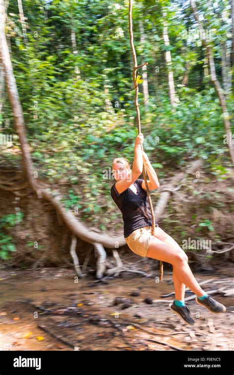 Young Woman Swinging On A Vine In The Jungle Tropical Rain Forest