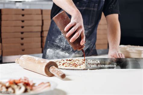 피자를 요리 가공은 토마토 소스를 부 어 균일 한 블루 앞치마에 요리사 베이커의 근접 촬영 손 주방에서 요리 기술에 대한 스톡 사진 및 기타 이미지 Istock