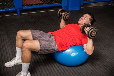 A Fit And Athletic Asian Guy Does Swiss Ball Dumbbell Chest Press