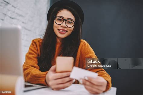 기술을 사용 하면서 카메라를 보고 있는 젊은 귀여운 미소 여자 방문 카드에서 전화로 정보를 입력 하는 더 나은 시력을 위한 안경에 아름 다운 쾌활 한 힙스터 소녀의 절반