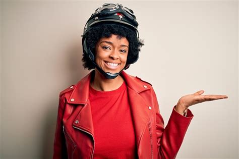 젊은 아프리카계 미국인 Afro 오토바이 여자 곱슬 머리를 입고 오토바이 헬멧 미소 쾌활 한 제시 하 고 카메라를 보고