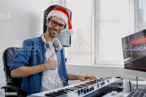 엄지 손가락 메리 크리스마스와 행복한 새해 녹음 스튜디오에서 피아노 키에 작곡가 손 음악 제작 기술 크리스마스 모자를 쓴 남자는