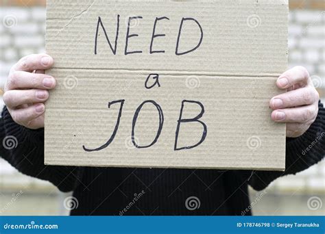 Unemployed Person Holding A Cardboard Sign With A Inscription Need A