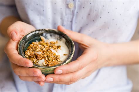 Muesli 그릇으로 젊은 여자 아침 식사 시리얼 그릇에 요구르트 귀리 호박 씨앗 견과류와 함께 홈메이드 그 라 놀라를 들고 손입니다 건강 한 간식입니다 사람들에 대한 스톡