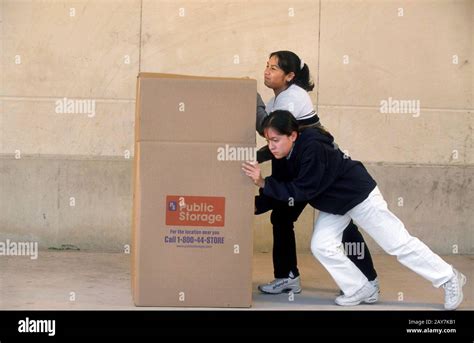 Two Fourteen Year Old Hispanic Girls Push Heavy Box To Test Static
