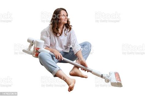 부엌에 무선 휴대용 진공 청소기를 가진 행복한 여자 흰색 배경에 고립되어 있습니다 웃는 여자가 배터리가 달린 진공 청소기로 아파트 바닥을 청소합니다 35 39세에 대한 스톡