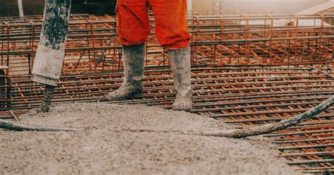 부츠와 주황색 보호복을 입은 건설 현장 작업자가 콘크리트를 쏟고 있습니다 사진 Unsplash의 산업 이미지