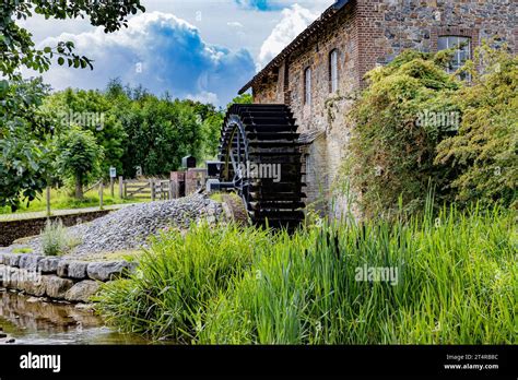 Old Eper Or Wingbergermolen Water Mill On Geul River Wild Grass And Trees On Plot Against Cloud