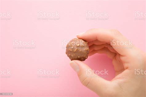 밝은 분홍색 테이블 배경에 갈색 초콜릿 트러플을 들고 젊은 성인 여성 손가락 파스텔 색상 달콤한 간식 근접 촬영 하향 보기 개념에 대한 스톡 사진 및 기타 이미지 Istock