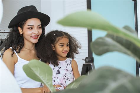 아름다운 행복한 성인 어머니 교육 그녀의 혼합 인종 아프리카 작은 귀여운 딸 소녀를 묶어 행복으로 미소 짓고 함께 만들고 차려 입고 아늑한 집에서 거울을 바라 봅니다 2명에