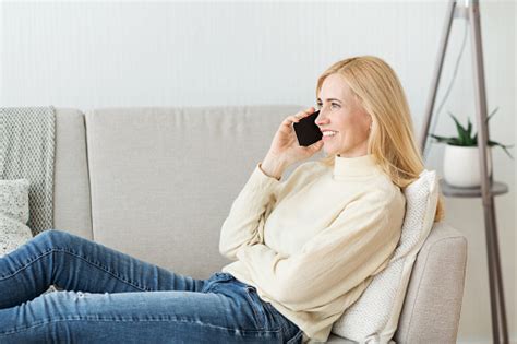 자연 채광 아래에서 집에서 스마트 폰으로 이야기하면서 소파에서 휴식을 취하는 여자 45 49세에 대한 스톡 사진 및 기타 이미지 45 49세 Brand Name