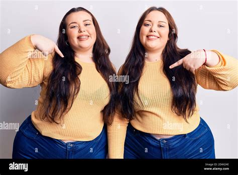 Young Plus Size Twins Wearing Casual Clothes Looking Confident With Smile On Face Pointing