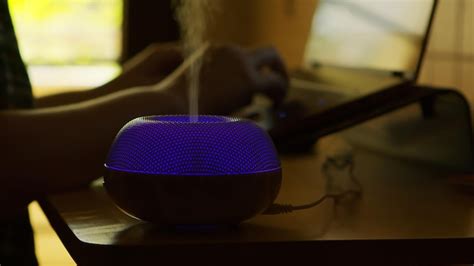 Premium Photo Blue Led Light Aroma Oil Diffuser On Table And Freelancer Woman Working From