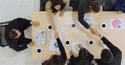 그룹 비즈니스 사람들은 사무실의 회의 테이블에서 악수하고 탑 뷰에서 자신감 있는 샷을 합니다 젊은 사업가와 여성 사업가들은 투자 거래에 대한 동의를 표명합니다 사진