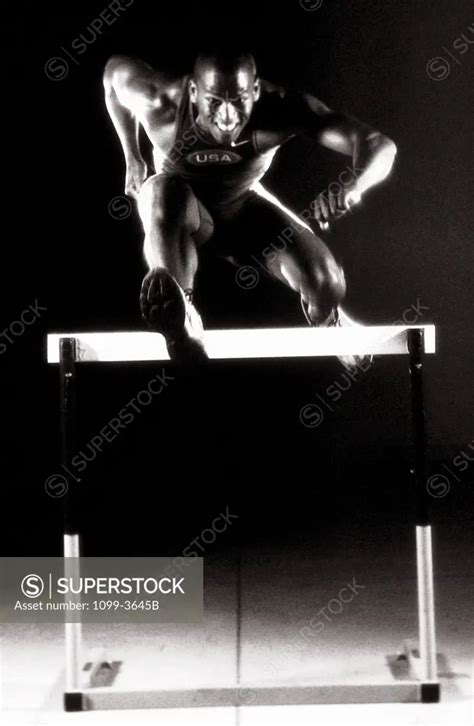Portrait Of A Babe Man Jumping Over A Hurdle SuperStock