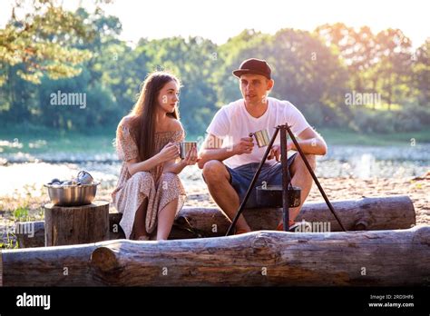 Young Guy And Girl Sit On Logs In Nature And Communicate Outdoor