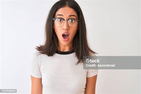 캐주얼 한 티셔츠와 안경을 쓰고 고립 된 흰색 배경 위에 서있는 중국 여성은 놀라움과 두려움 흥분된 얼굴로 두려워하고 충격을 받았습니다 아시아인에 대한 스톡 사진 및 기타