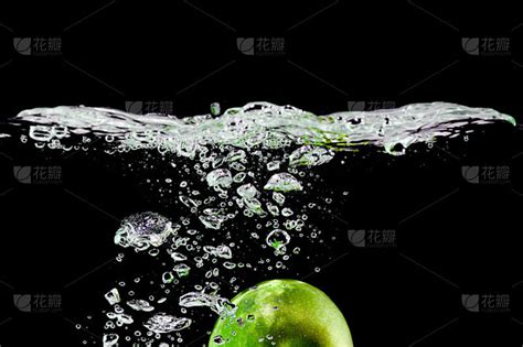 青苹果在黑色背景下落入水中