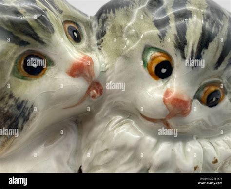 Two Ceramic Cat Figurines On A White Table Facing Each Other In An