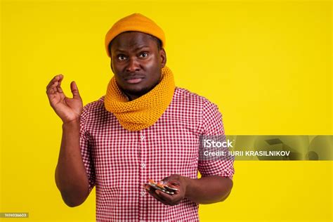 니트 스카프와 모자가 달린 빨간 체크 무늬 셔츠를 입은 젊은 아프리카 계 미국인 남성은 스튜디오 노란색 배경에서 발열과 오한으로 기분이 좋지 않습니다독감과 바이러스 개념