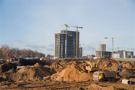 건설 크레인과 건물의 배경에 건설 현장에서 굴삭기 백호는 기초의 땅을 파고 폭풍 하수 파이프를 누워 물 주요 시스템의 설치 건설 산업에 대한 스톡 사진 및 기타 이미지