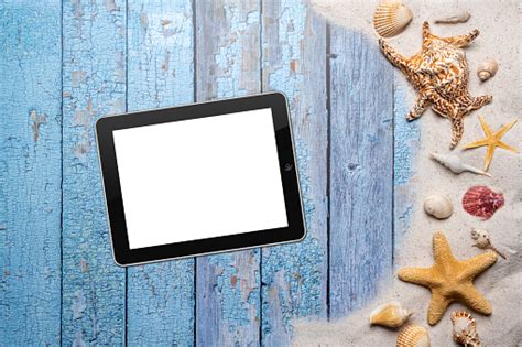 여름 해변 휴가 컨셉으로 자유로운 텍스트 공간을 즐길 수 있다 평면도 빈 태블릿 큰 바다 별과 조개 오래된 파란색 나무 판자 배경에 다양한 조개와 고운 해변 모래가 있는