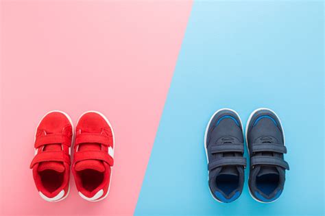 밝은 파란색 분홍색 테이블 배경에 어린 소년과 소녀를위한 빨간색과 어두운 파란색 스포츠 신발 파스텔 색상 어린이 신발 텍스트의 빈 장소입니다 하향 보기 반이 채워진에 대한