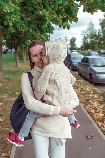 젊은 가족 여자 어머니는 그녀의 팔에 아이를 운반 후드와 스웨터에 어린 소년 도시를 산책 육아와 사랑을 양육의 개념 부모의 지원 가을과 봄 낮 따뜻한 옷 2명에 대한 스톡