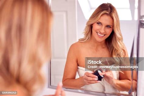 성숙한 여자 에 착용 보습기 보고 반사 에 욕실 거울 에 집에서 착용 수건 얼굴 크림에 대한 스톡 사진 및 기타 이미지 얼굴 크림 여자 40 44세 Istock