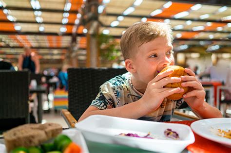 소년은 길거리 카페에서 점심을 먹고 있다 아이가 햄버거를 먹는다 어린이 메뉴 건강에 좋지 않은 음식에 대한 스톡 사진 및 기타 이미지 건강에 좋지 않은 음식 고기