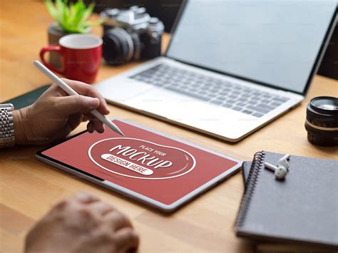 사무용품이 있는 나무 테이블에 스타일러스가 있는 모형 태블릿에 남성이 그림을 그리는 자른 샷 사진 Unsplash의 테이블 이미지