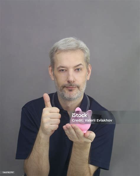 회색 머리와 회색 배경에 분홍색 돼지 저금통을 들고 수염을 가진 현명한 중년 남성 45 49세에 대한 스톡 사진 및 기타 이미지 45 49세 개념 검사 보기 Istock